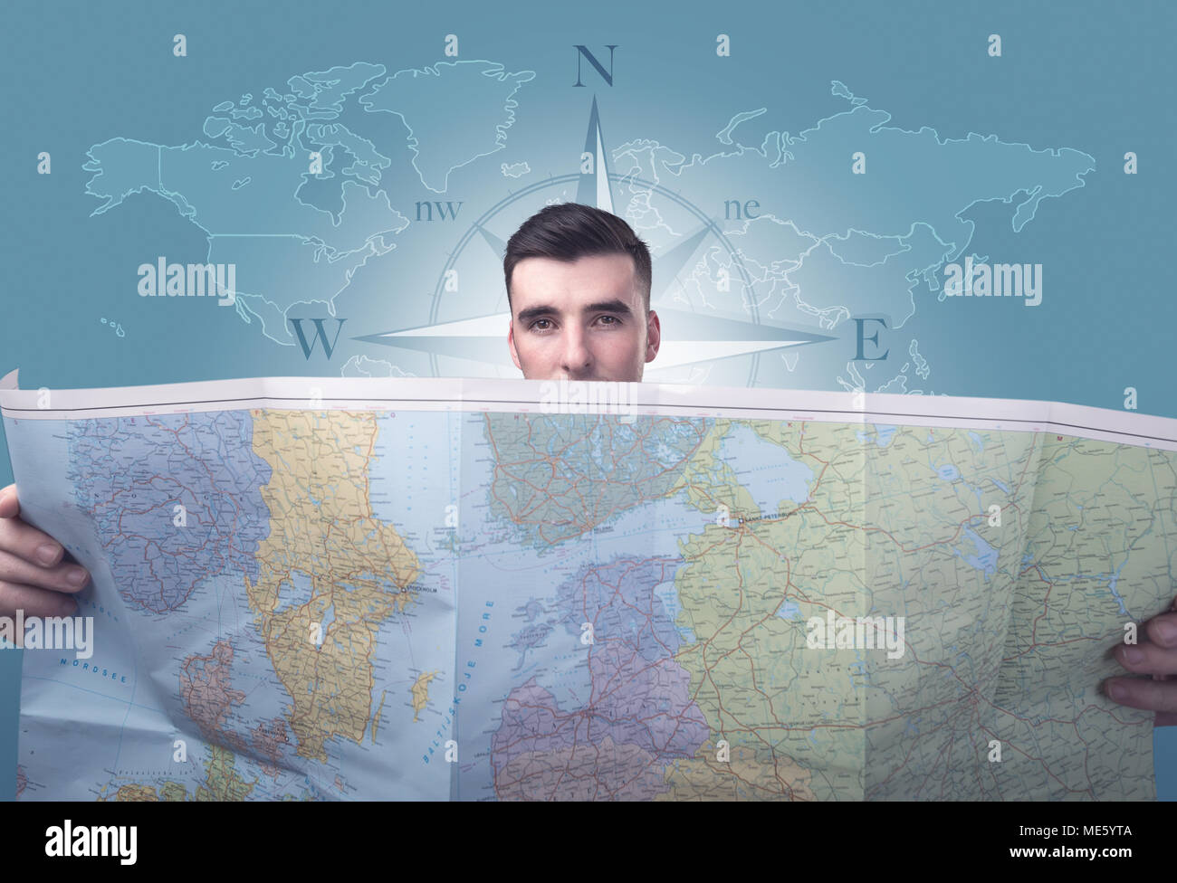 Handsome young man holding a map with a world map and a compass behind ...