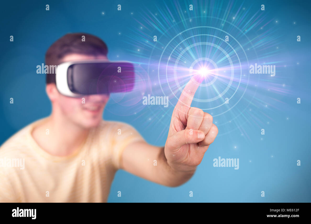 Young impressed man wearing virtual reality goggles with blue circles ...