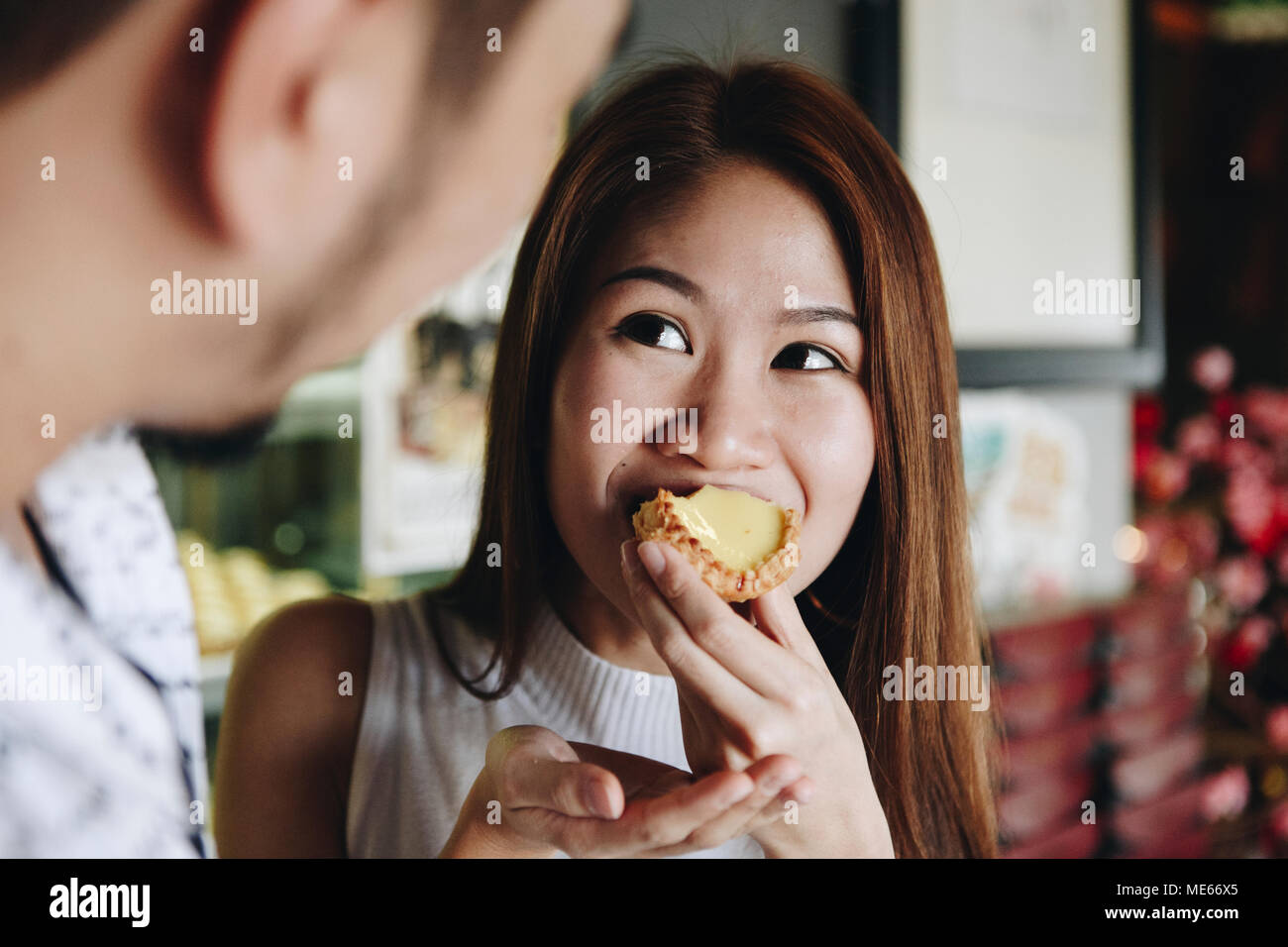 Asian girl having a bite of tart Stock Photo - Alamy