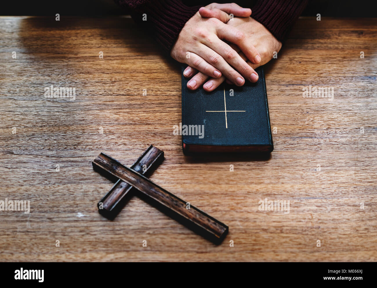Hands over bible on wooden table Stock Photo - Alamy