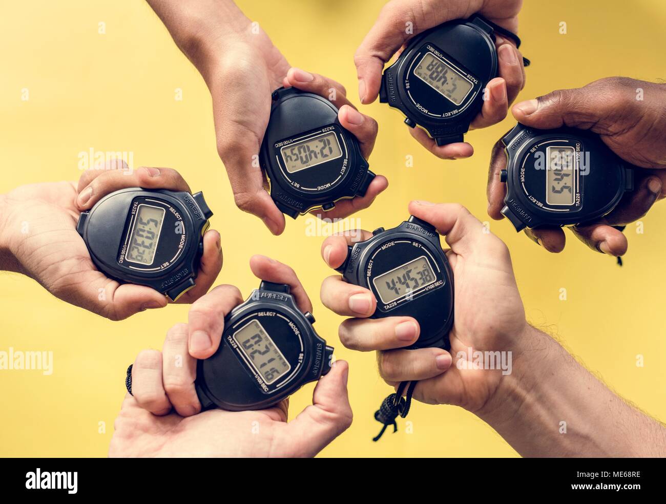 Closeup of hands holding stop watches with yellow background Stock ...