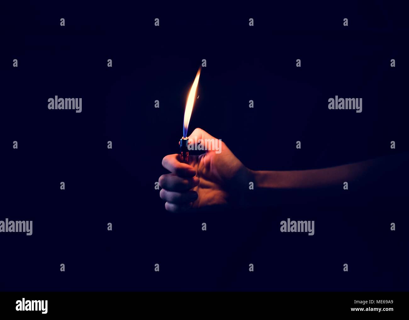 Hand holding lit lighter in the dark Stock Photo - Alamy