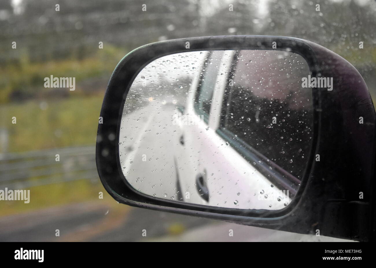 Reflections in a side view mirror of a car driving on the road. Rear ...