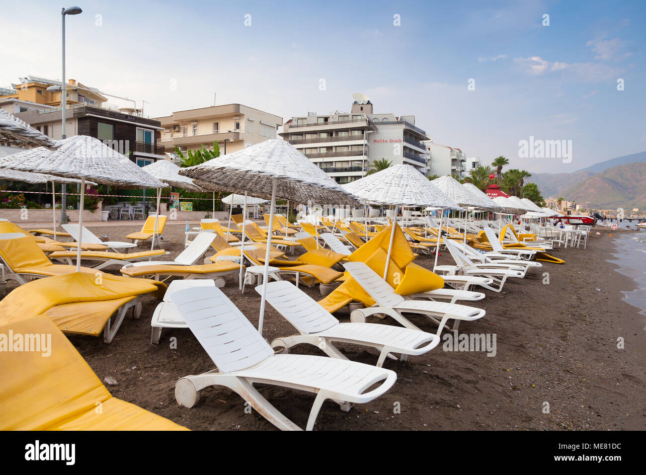 Sunbeds and yellow mattresses on the beach in Marmaris after heavy wind ...