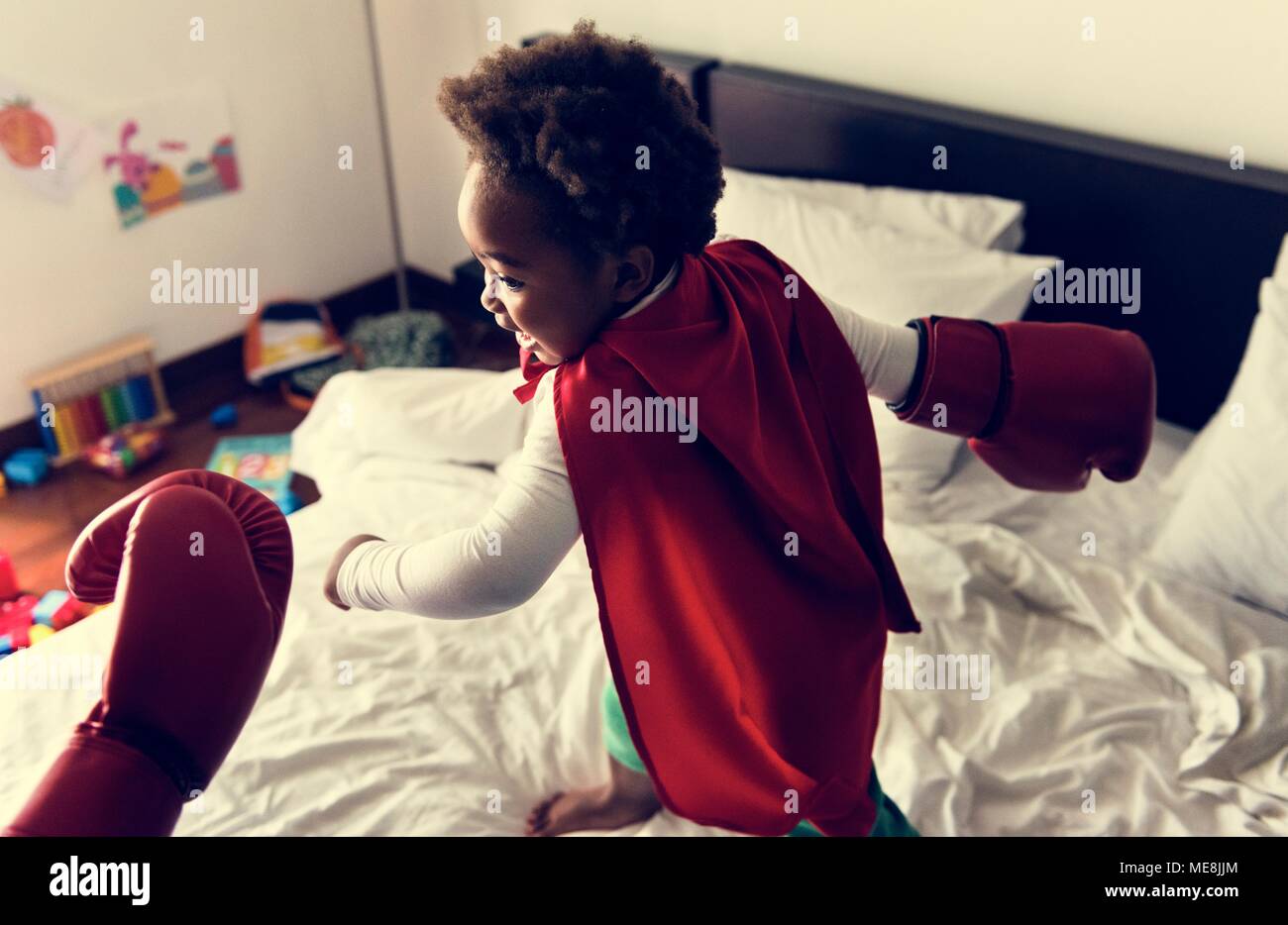 African descent kid wearing robe doing boxing with dad on the bed Stock ...