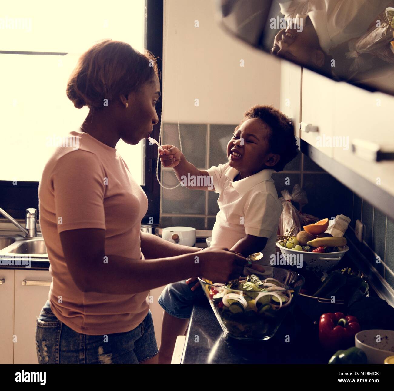 Black kid feeding mother with cooking food in the kitchen Stock Photo ...