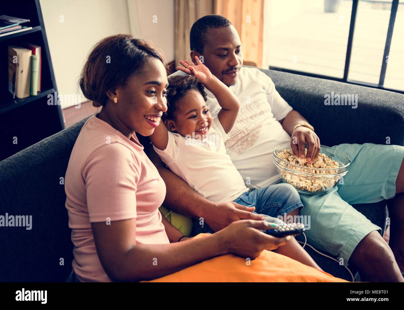 Black family eating popcorn while watching movie at home Stock Photo ...