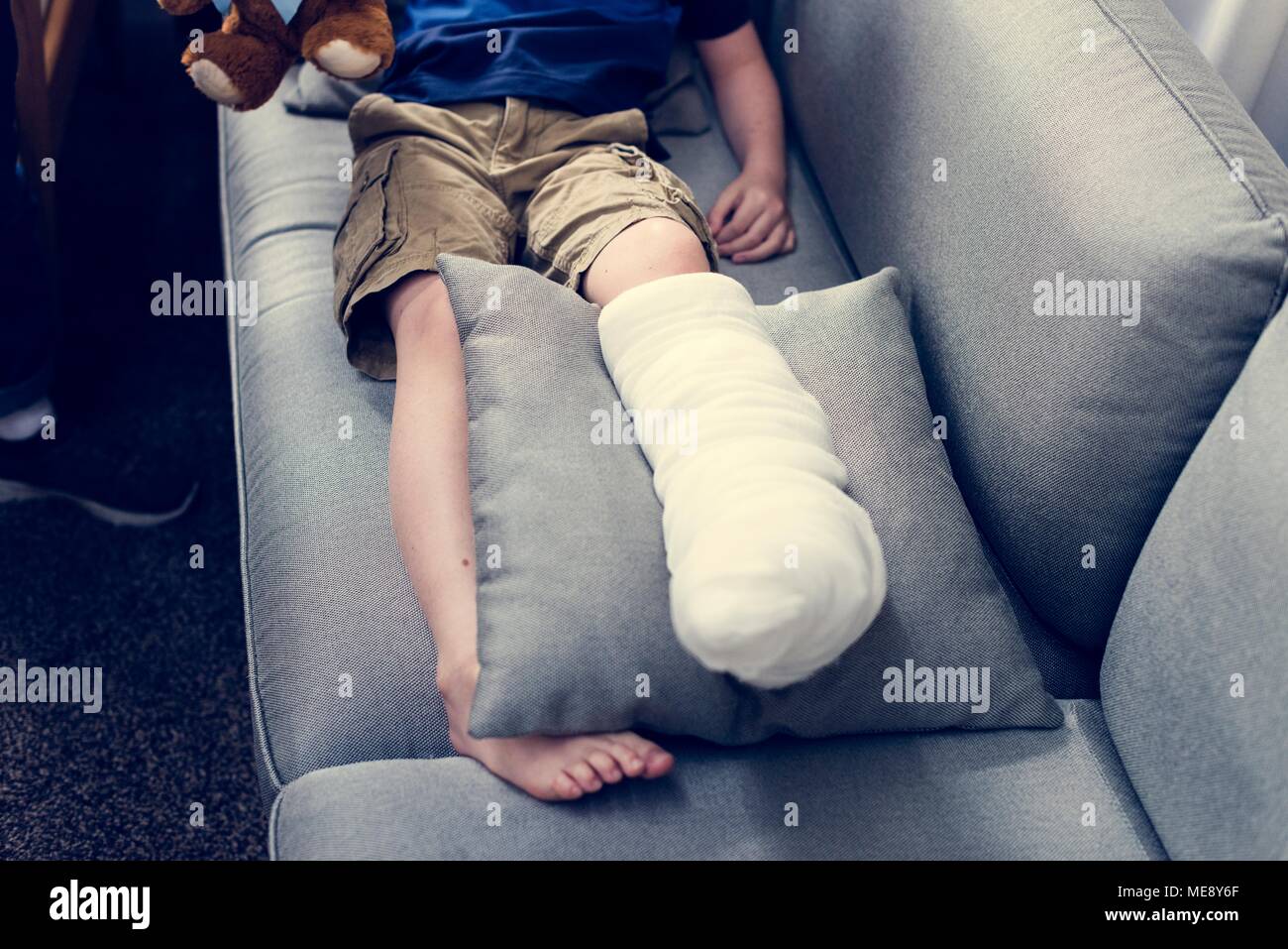 Kid with injured leg is sitting on the couch Stock Photo - Alamy