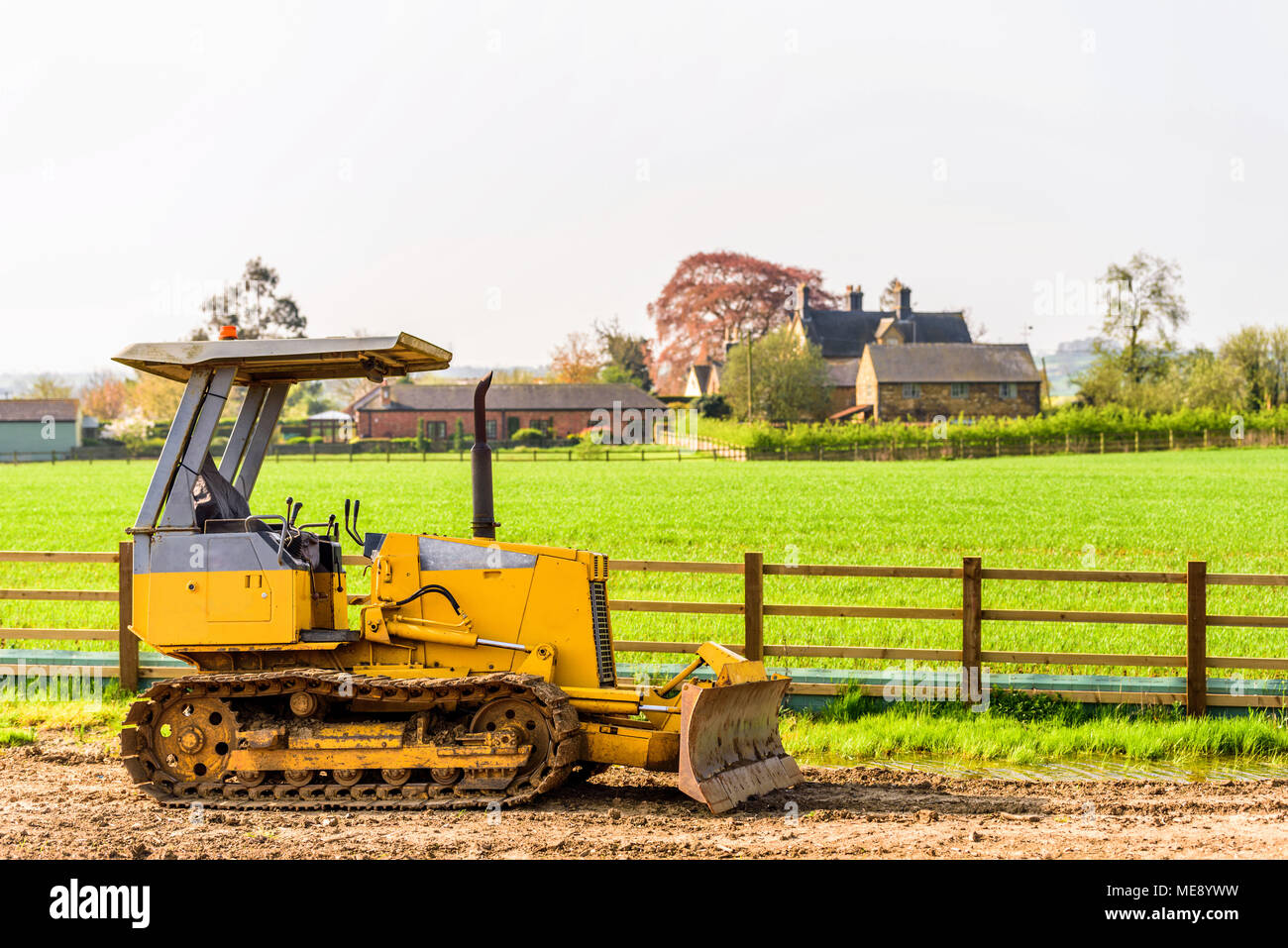 A small yellow construction bulldozer over British countryside Stock ...