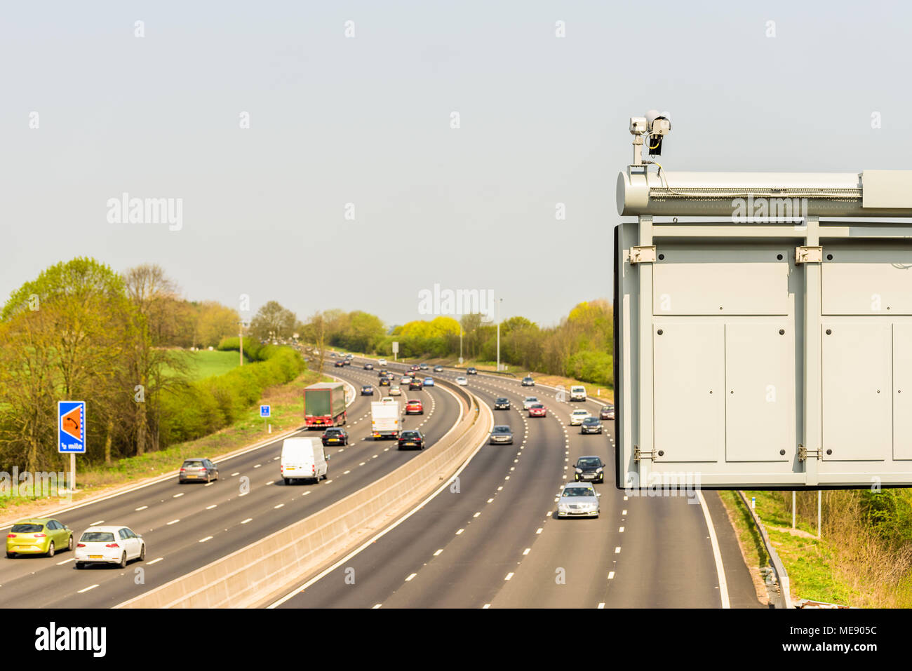 Sunny day view of UK motorway traffic with CCTV camera on foreground ...