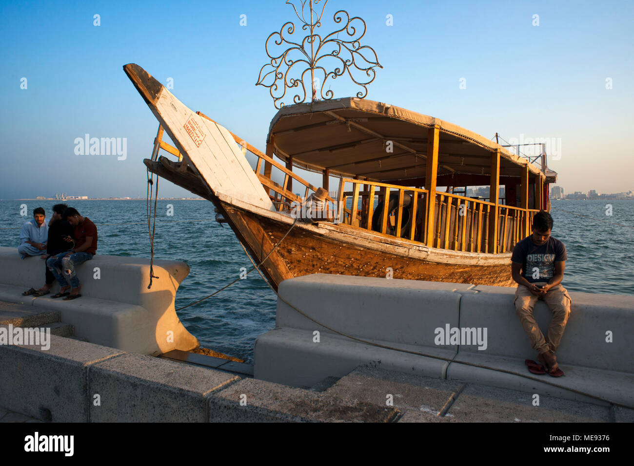 Dhow traditional sailing for tourists in Corniche promenade. Behind the ...