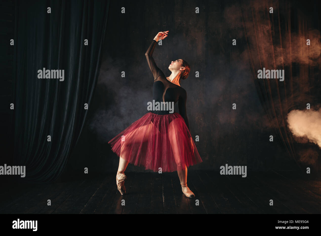 Ballet dancer in red dress dancing on the stage in theatre. Graceful ...