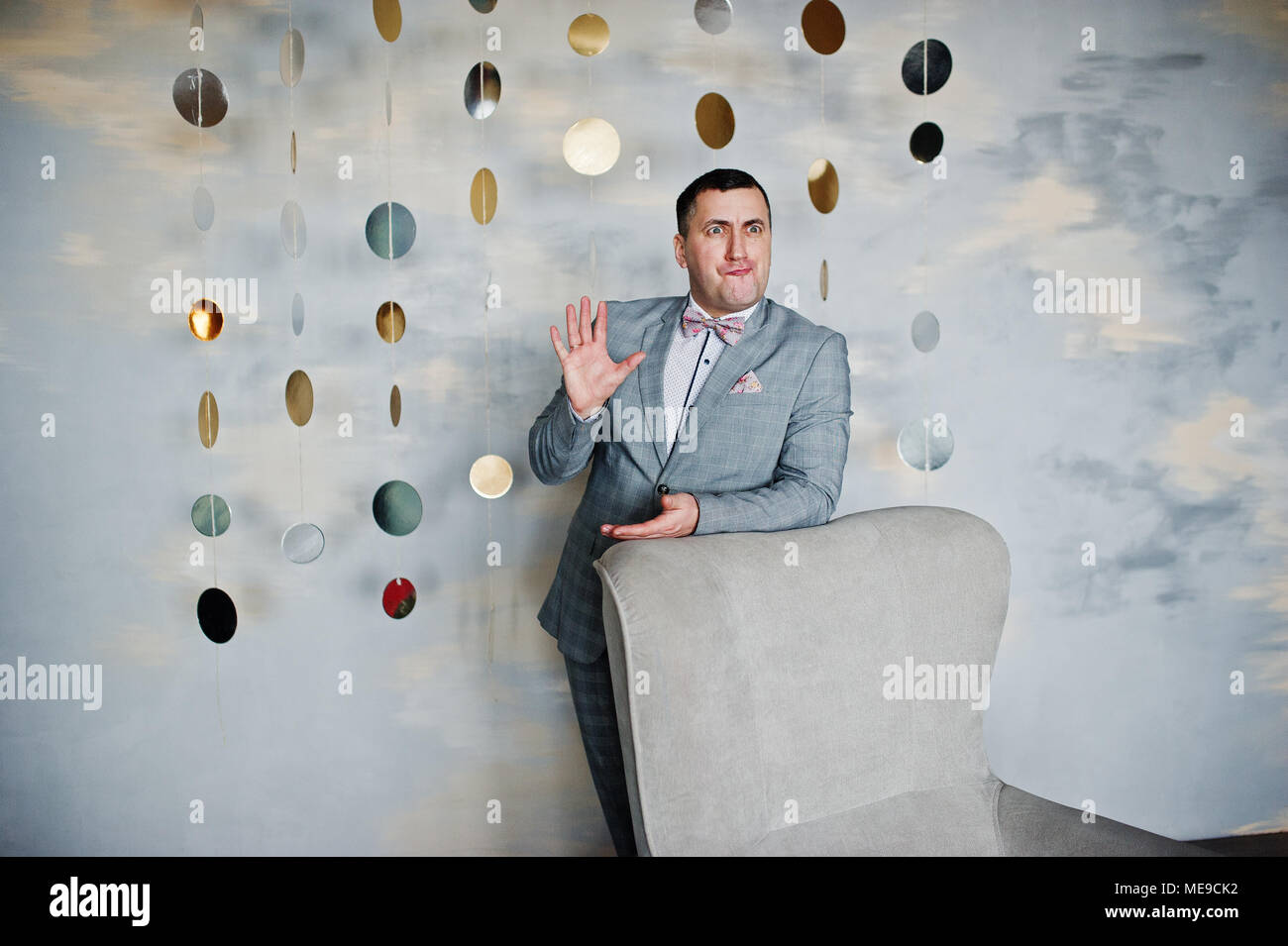 Studio portrait of man in suit near chair Stock Photo - Alamy
