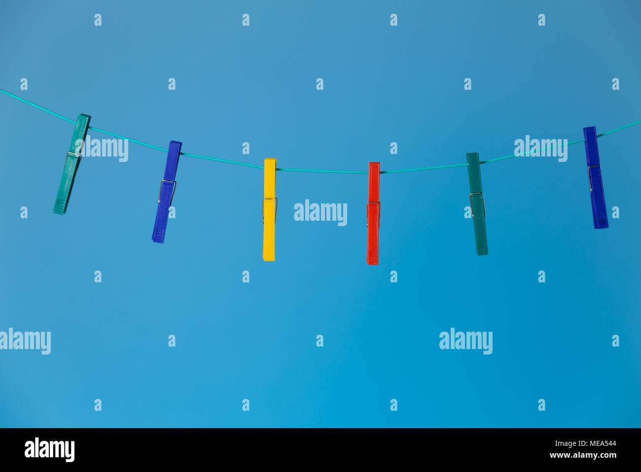 Group of clothes pegs on rope on blue background Stock Photo - Alamy