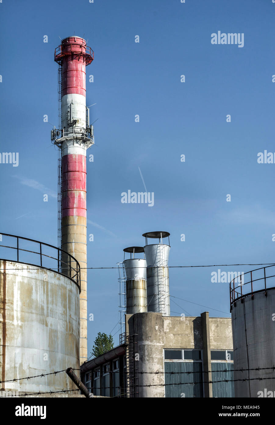 Old industrial oil heating plant with red smoke and blue clear sky ...
