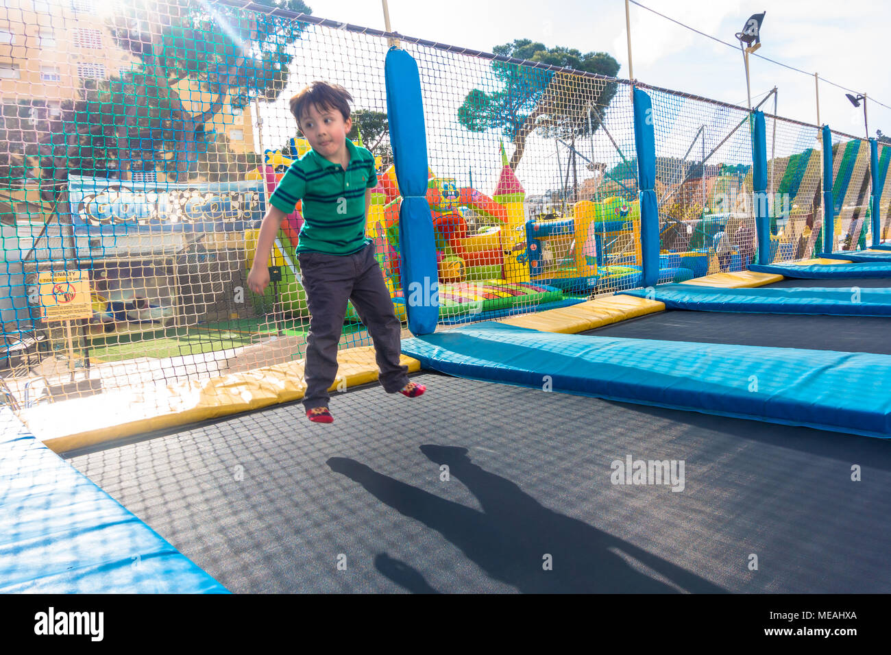 A young boy having fun jumping on a trampoline outside while on holiday ...