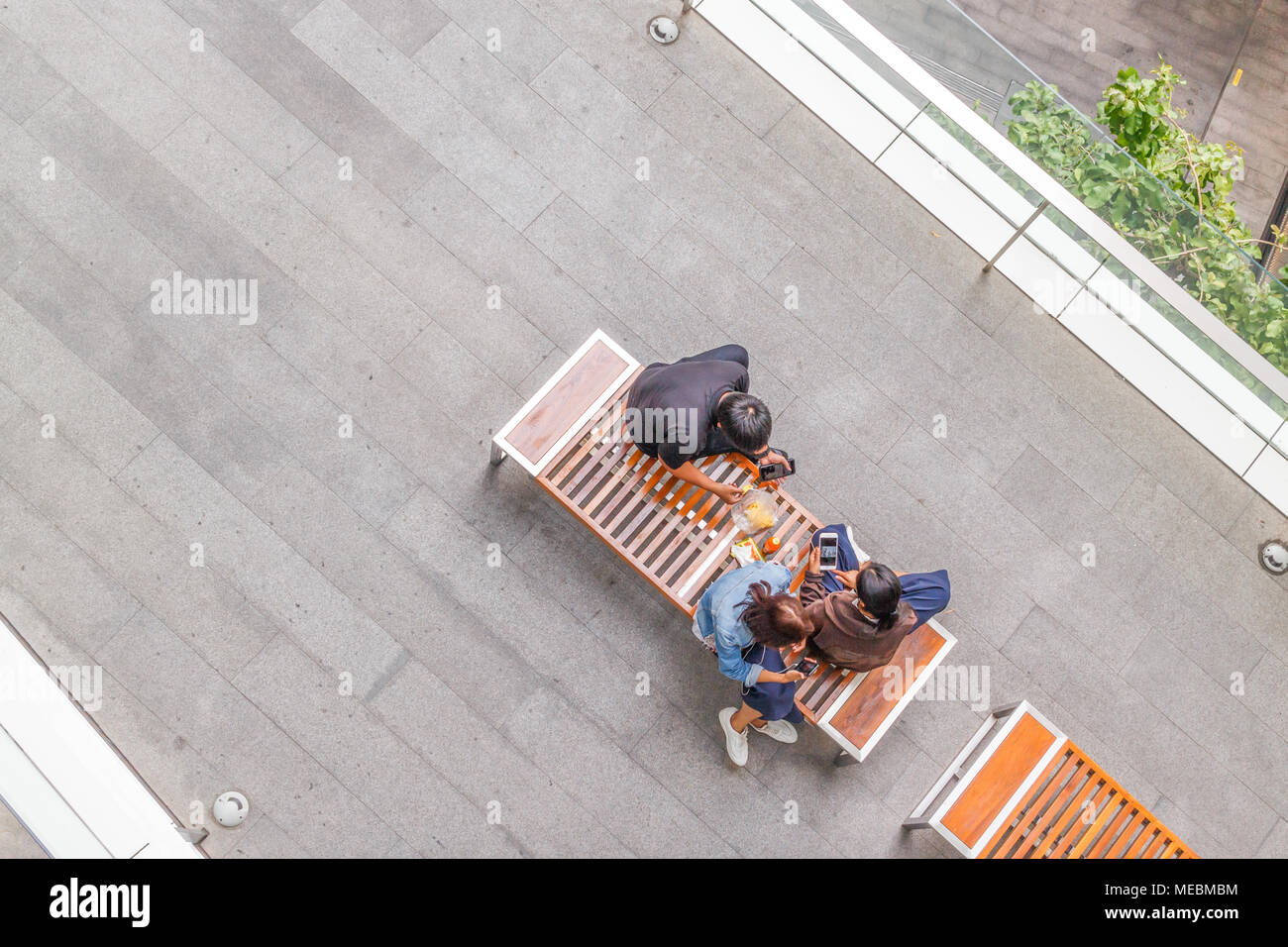 Overhead view of people sat on a bench using their mobile phones ...