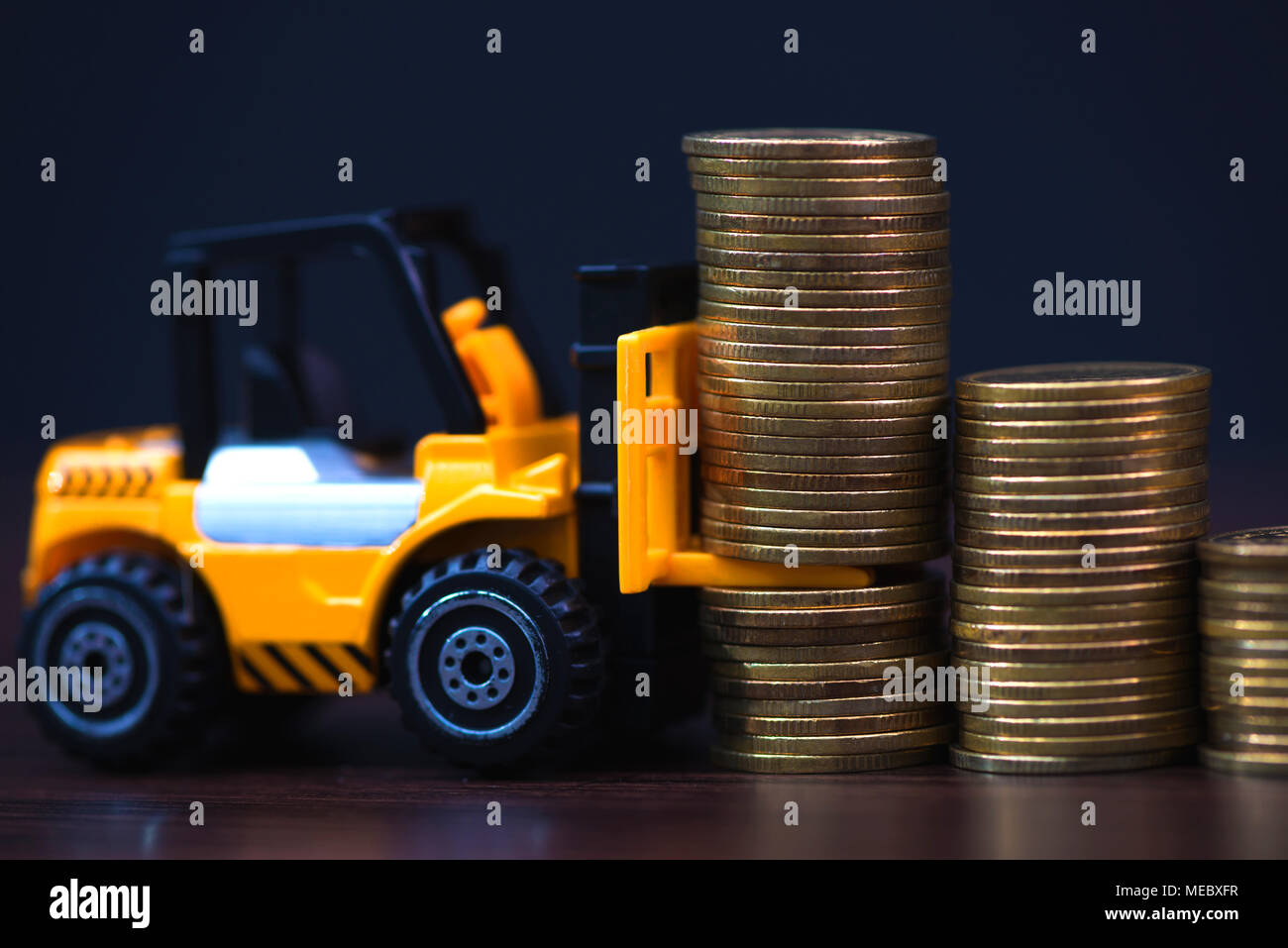Mini forklift truck loading stack coin with steps of gold coin in dark ...