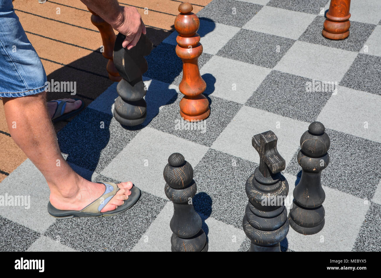 Man moves chess piece on large outdoors chess board. Challenging game ...