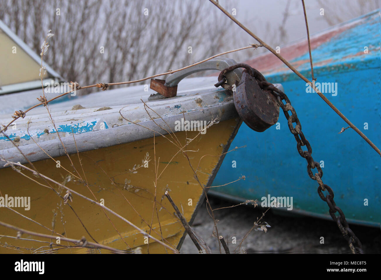 The iron boat is on the shore attached to a rusty castle with a chain ...