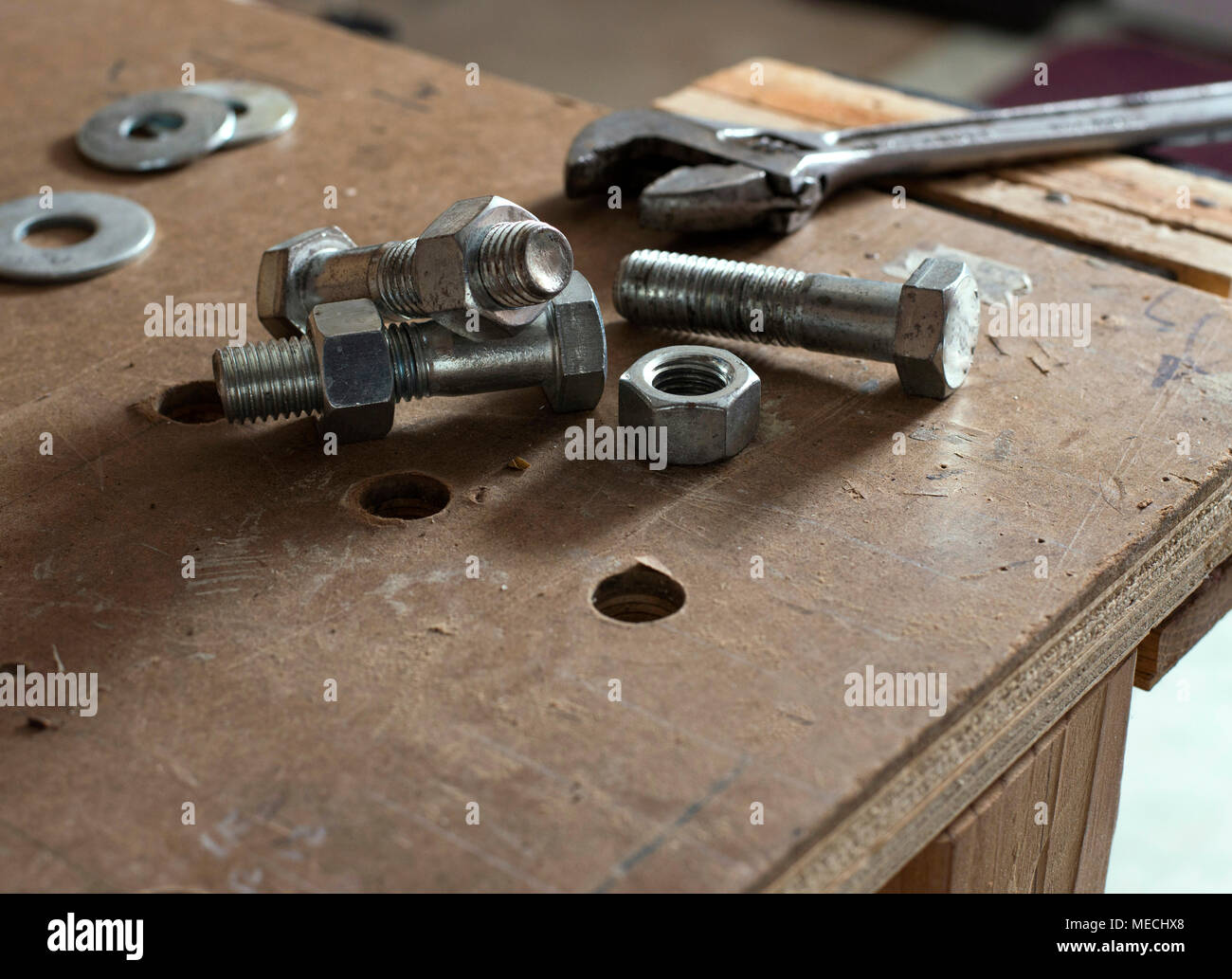 Nuts and bolts on workbench with wrench in background Stock Photo - Alamy