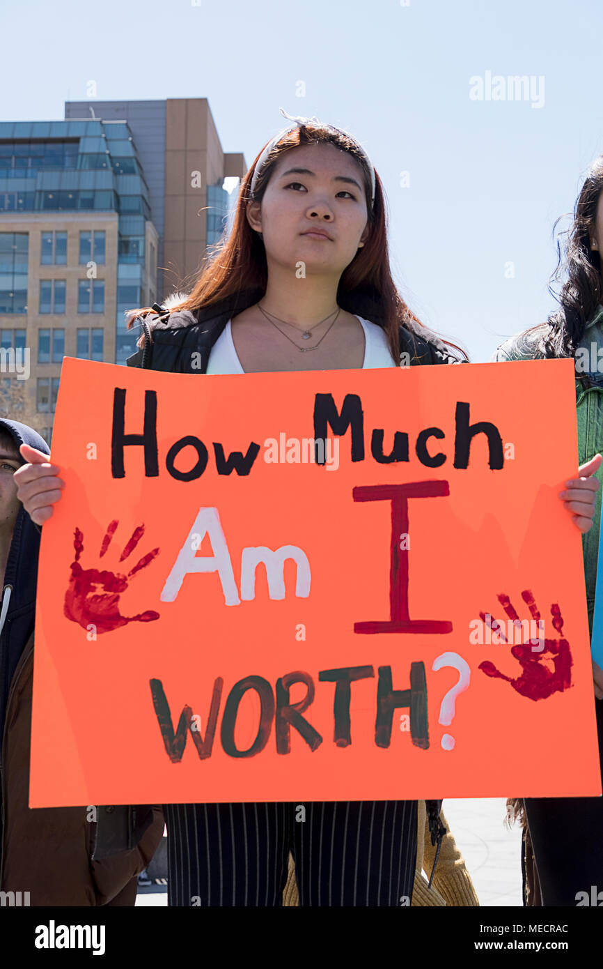 A young Asian girl with a sign asking HOW MUCH AM I WORTH at the ...