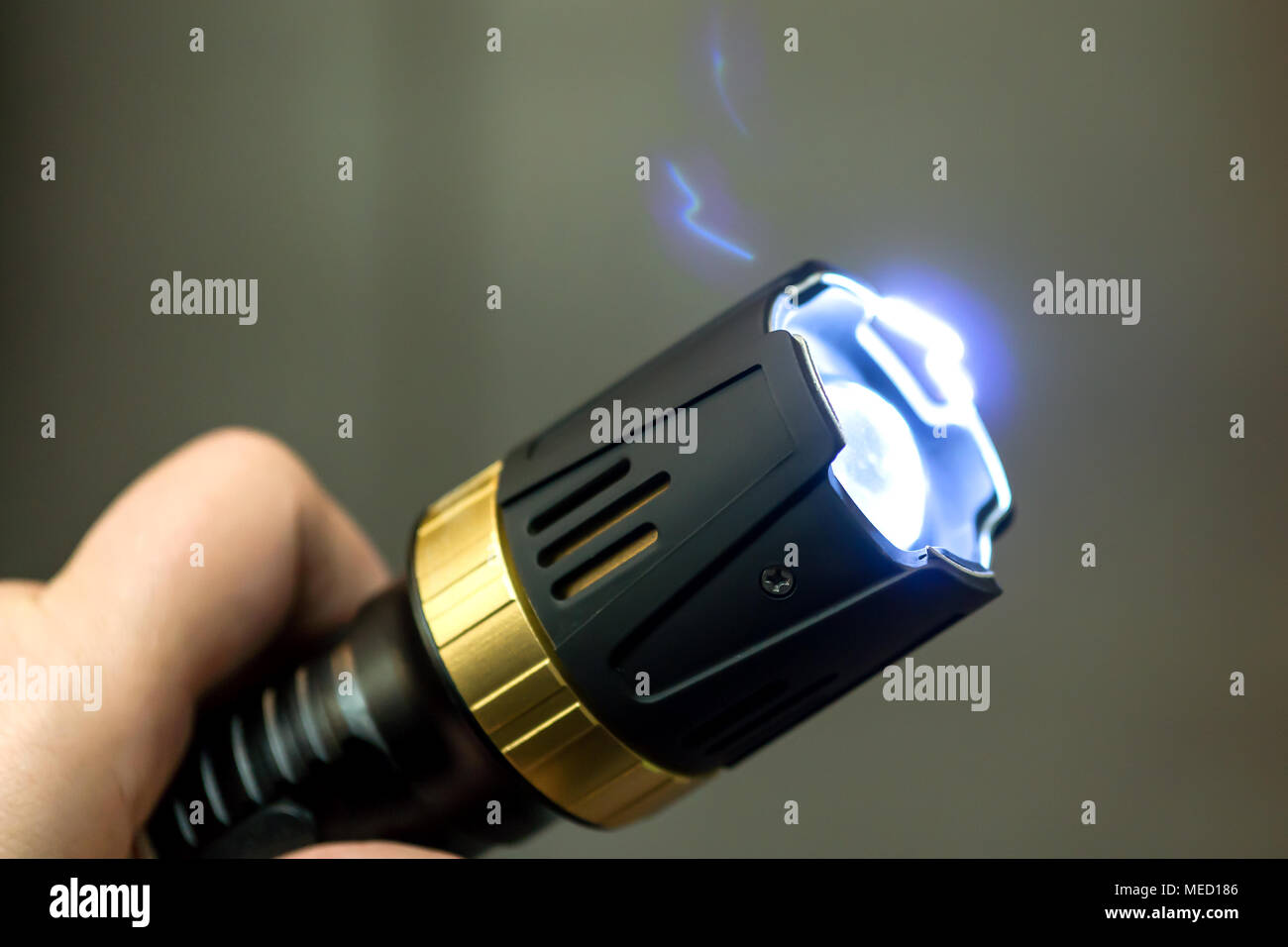 The hand holds a black metal shocker. Electric charge Stock Photo - Alamy