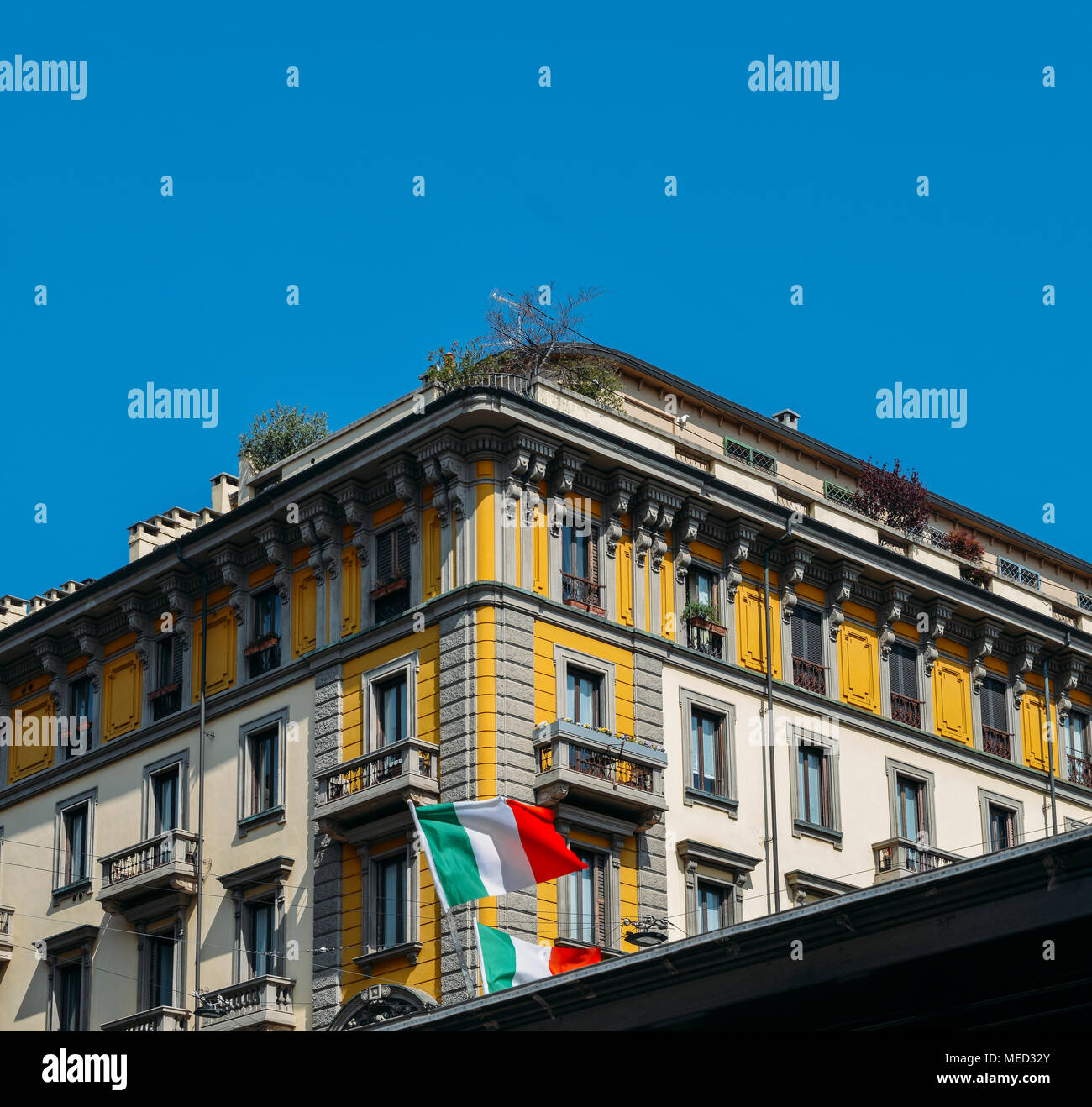 Italian flag against a vibrant Mediterranean colorful yellow building ...