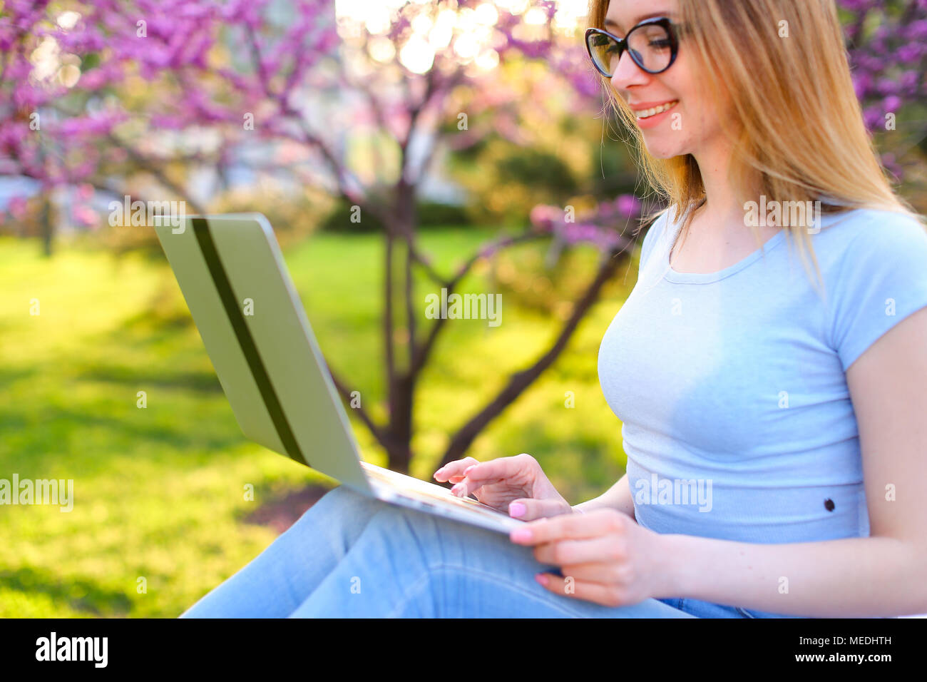 Cute girl typing message by laptop with blossom background Stock Photo ...
