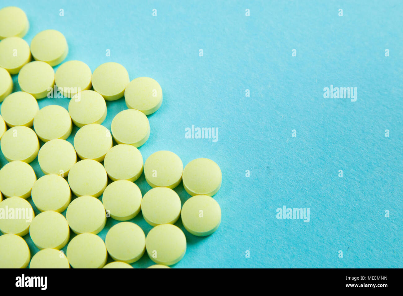 random yellow pills on blue isolated background Stock Photo - Alamy