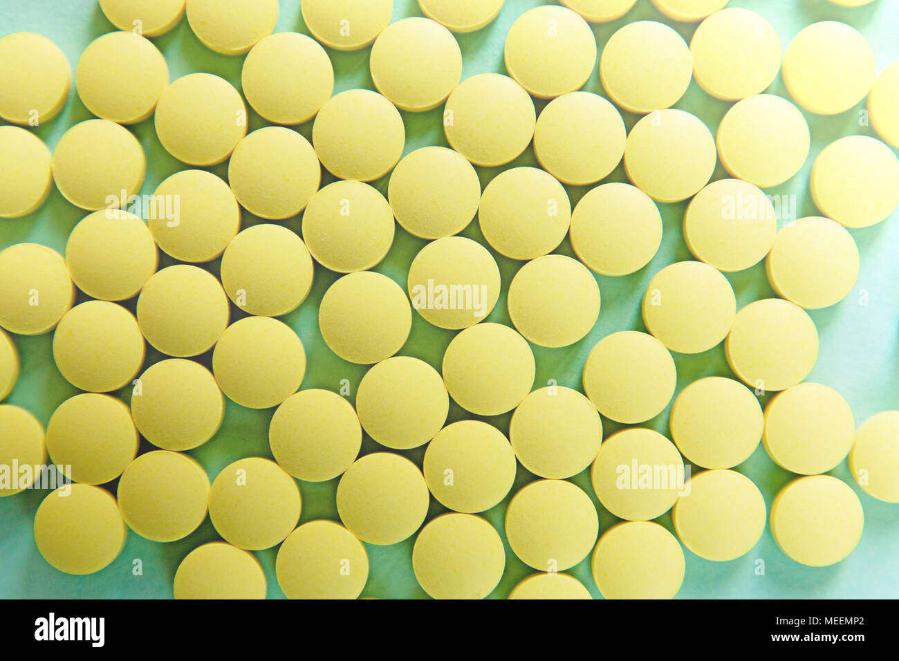 random yellow pills on blue isolated background Stock Photo - Alamy
