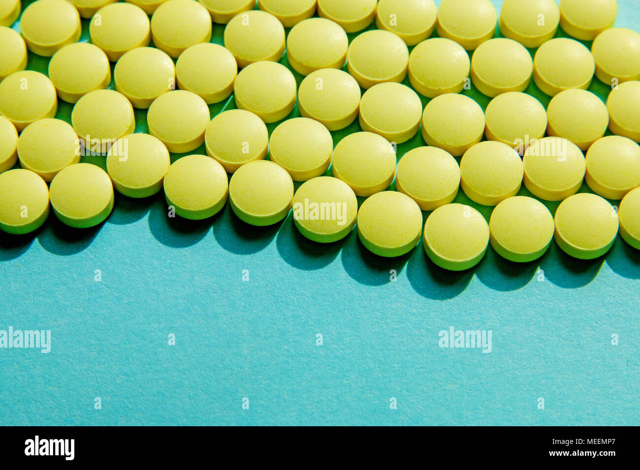random yellow pills on blue isolated background Stock Photo - Alamy