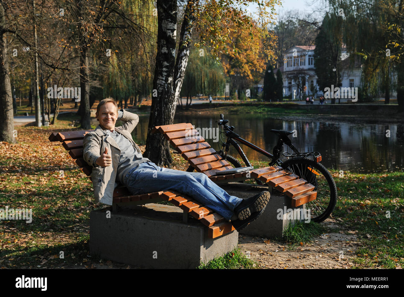 The man is resting on a lounger. He is showing a positive sign with his ...