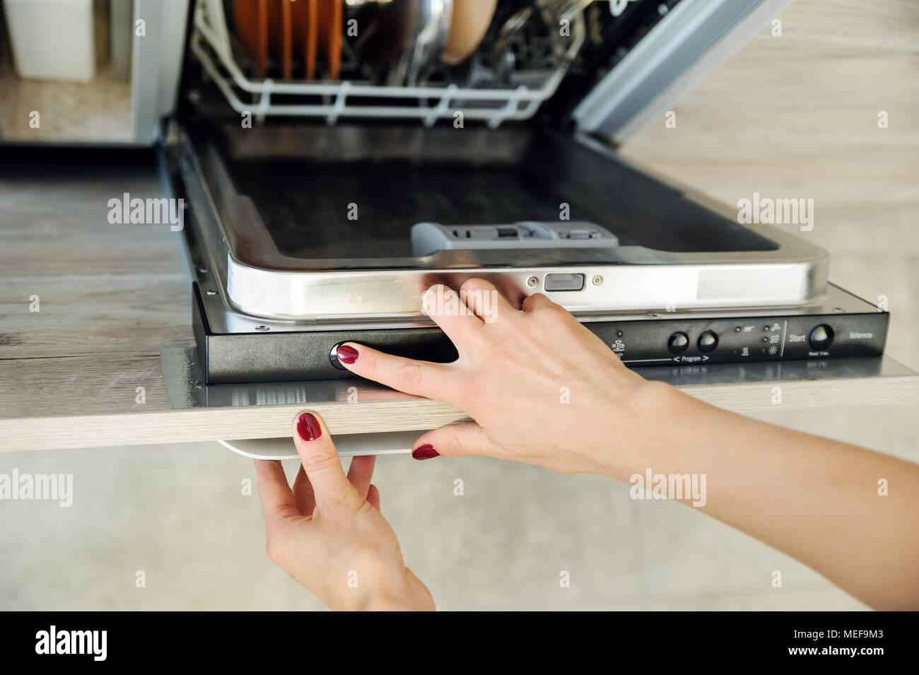 Run the dishwashing machine. Woman's finger pressing the Start button ...
