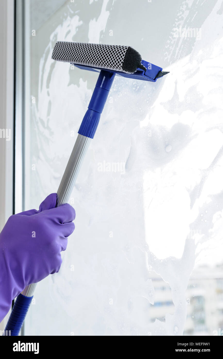 A man cleans the windows in the house. The hand in rubber glove is ...