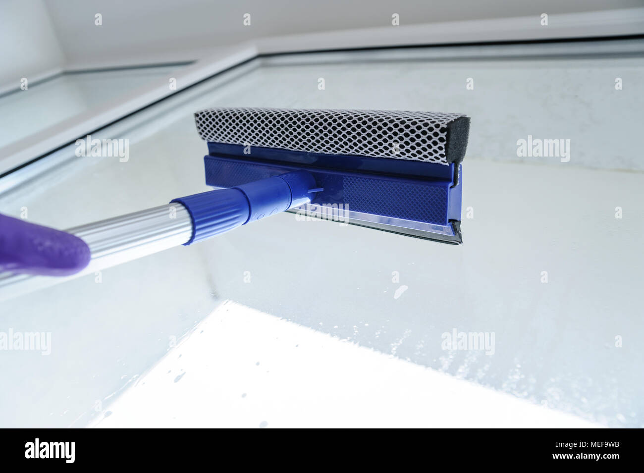 A man cleans the windows in the house. The hand in rubber glove is ...