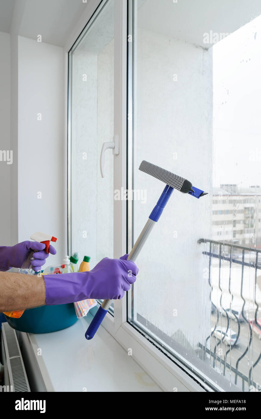 A man cleans the windows in the house. The hand in rubber glove is ...