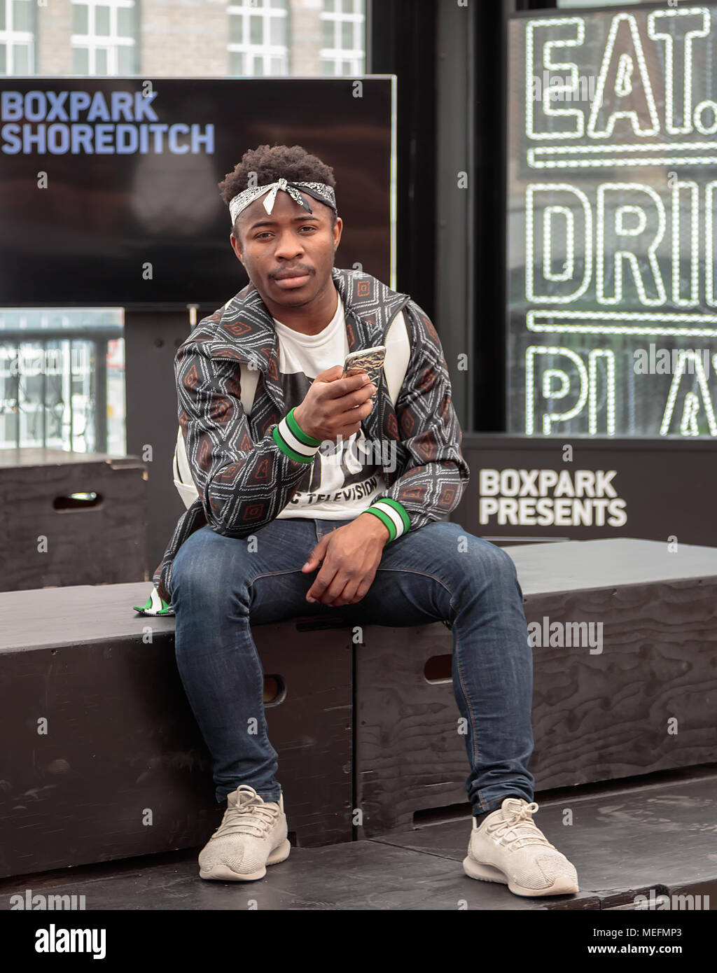 Portrait of a man sitting down on his phone looking at camera Stock ...