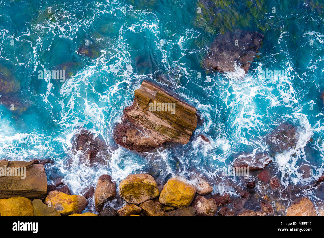 Top aerial view of blue waves crashing on rocky Australian coastline ...