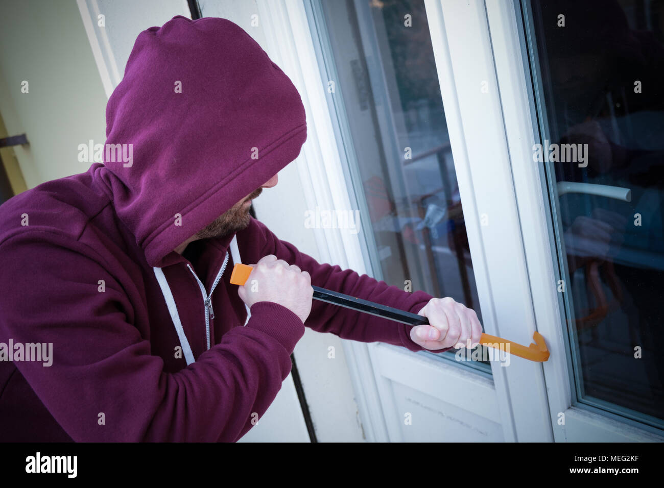 Hooded burglar forcing window lock to make a theft in a house Stock ...