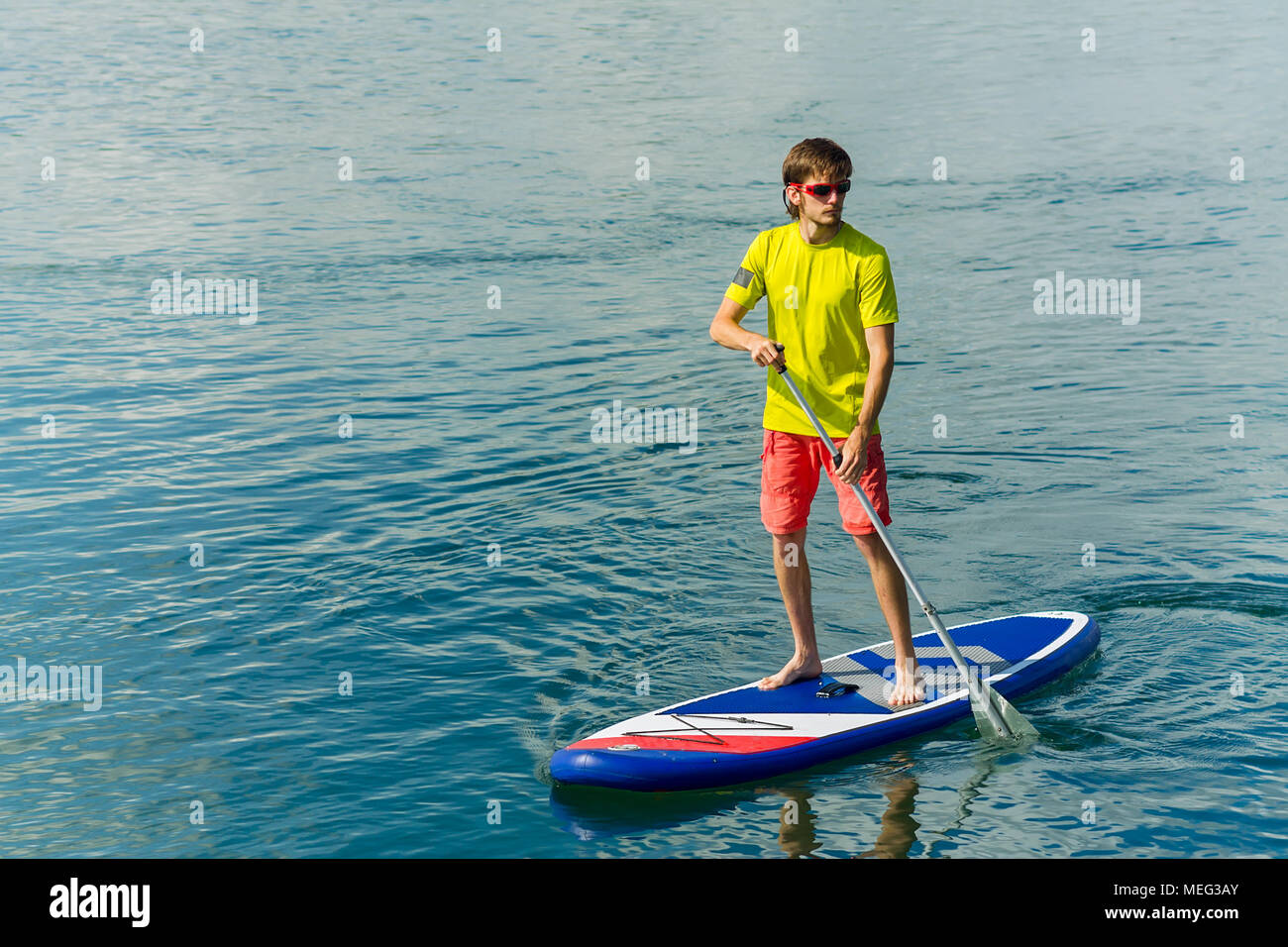 Sup surfing man stand up paddle boarder paddling at sunset on river ...