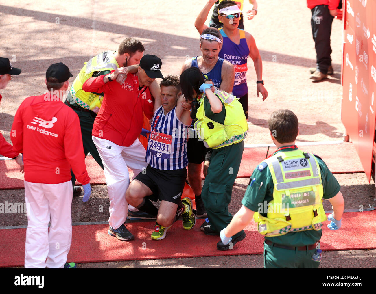 A runner is helped by medical staff after crossing the line during the ...