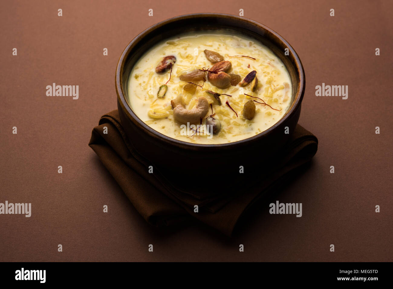 kheer or rice pudding is an Indian dessert in a brown terracotta bowl ...