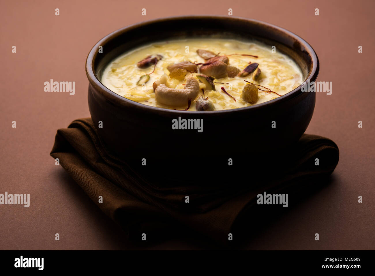 kheer or rice pudding is an Indian dessert in a brown terracotta bowl ...