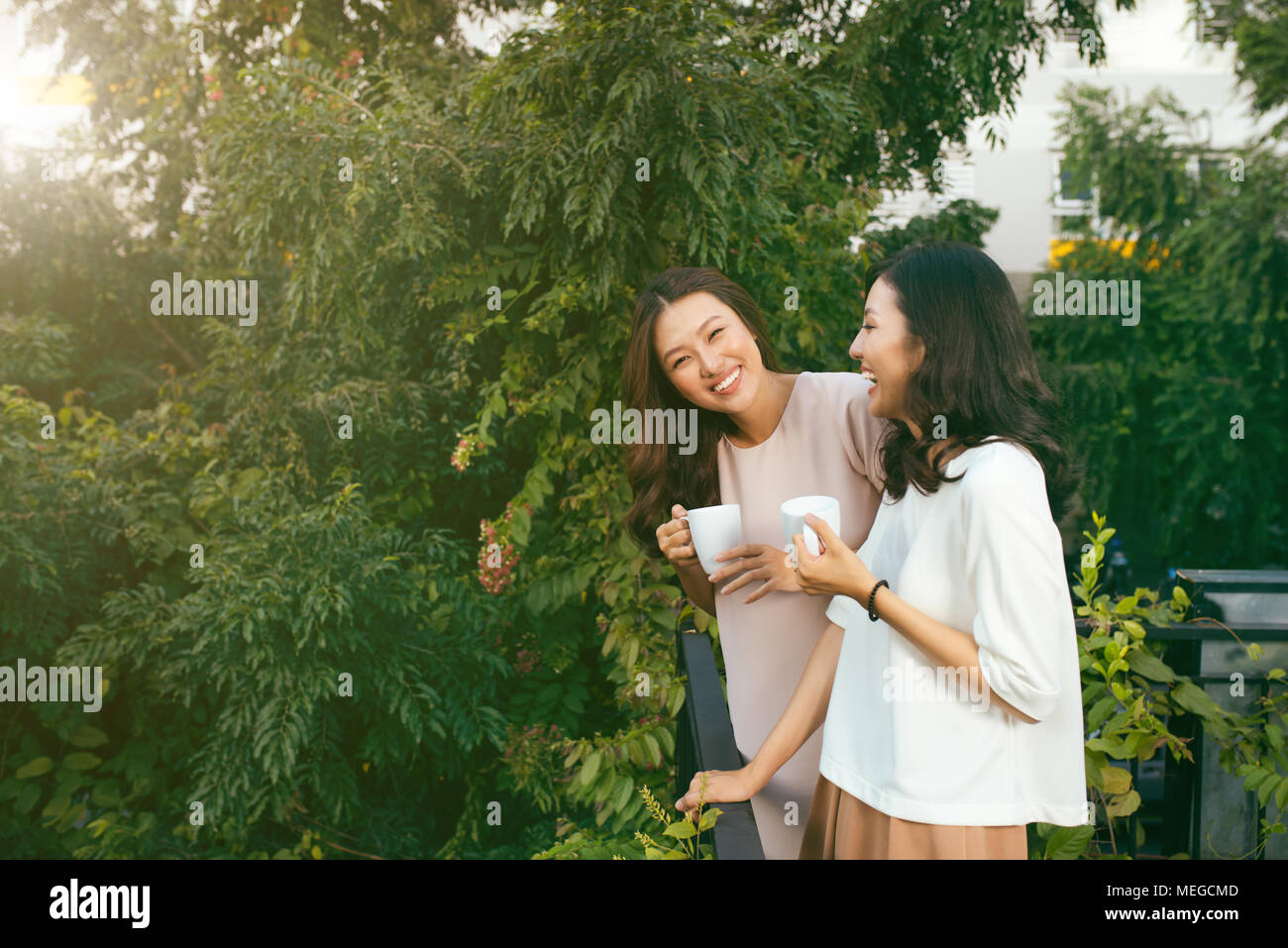 Happy young women friends well-dressed smiling while standing together ...