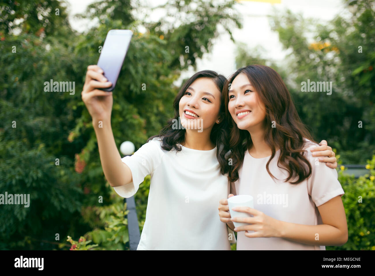 Happy young women friends well-dressed smiling while standing together ...