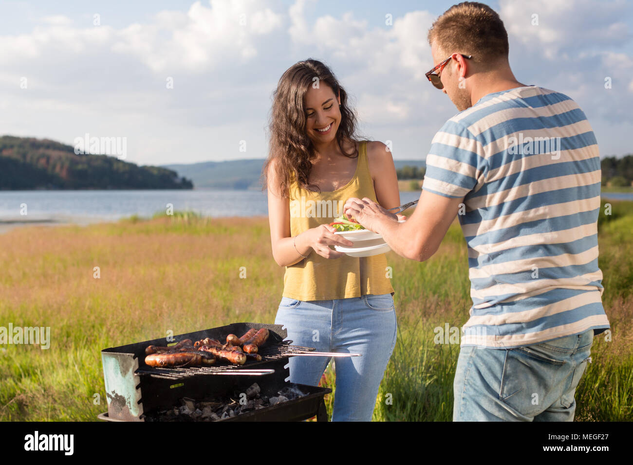 Man and woman having barbecue at lakeside in nature Stock Photo - Alamy