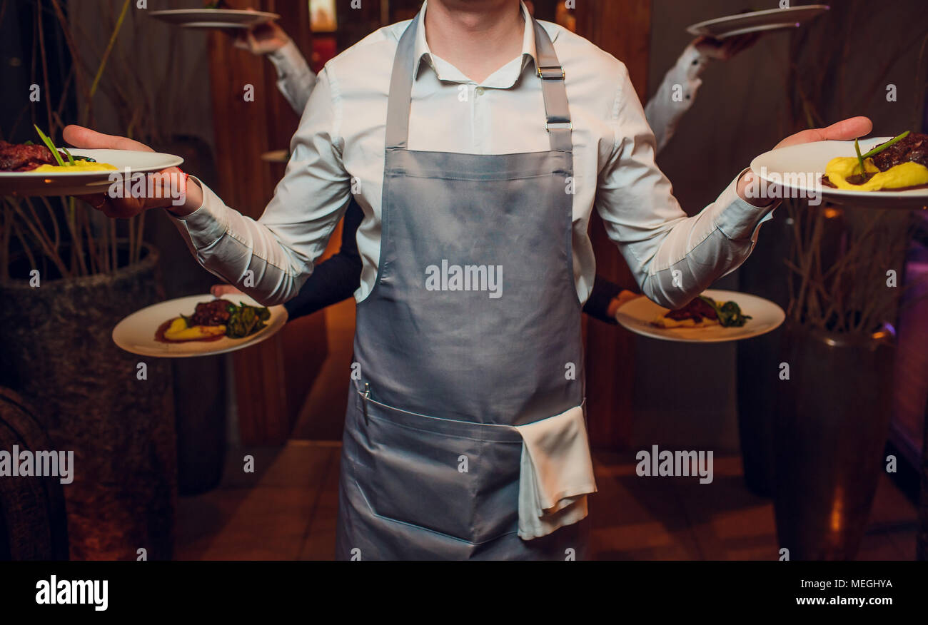 the waiter has a lot of hands, a lot of plates with food, the concept ...