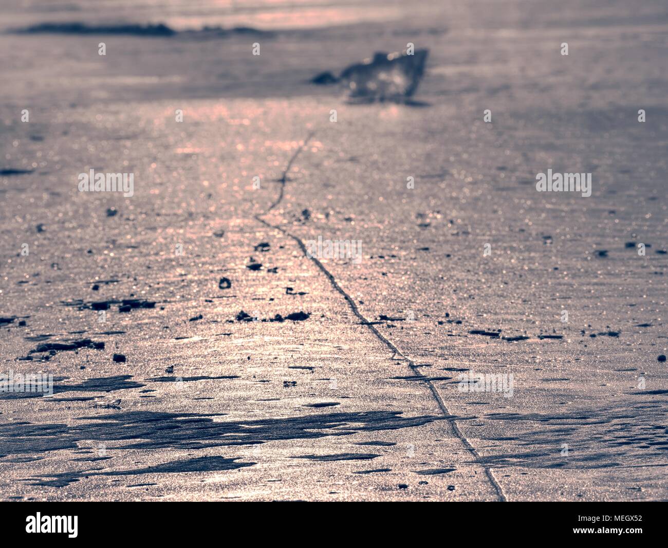 sparkling shards of cracked ice jut out on the frozen lake. The light ...