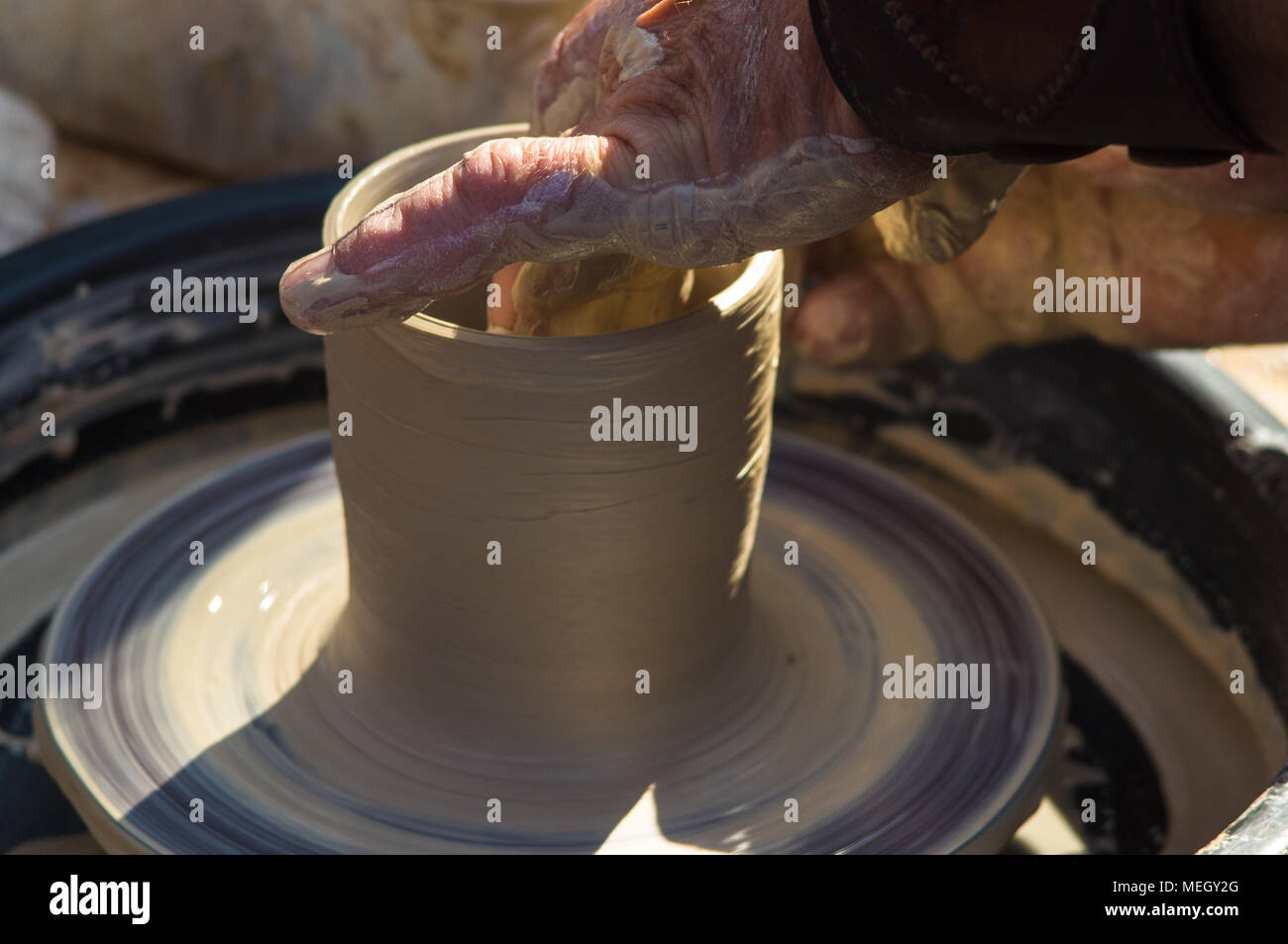 adult hand fed baby's hands to work with a potter's wheel, close up ...